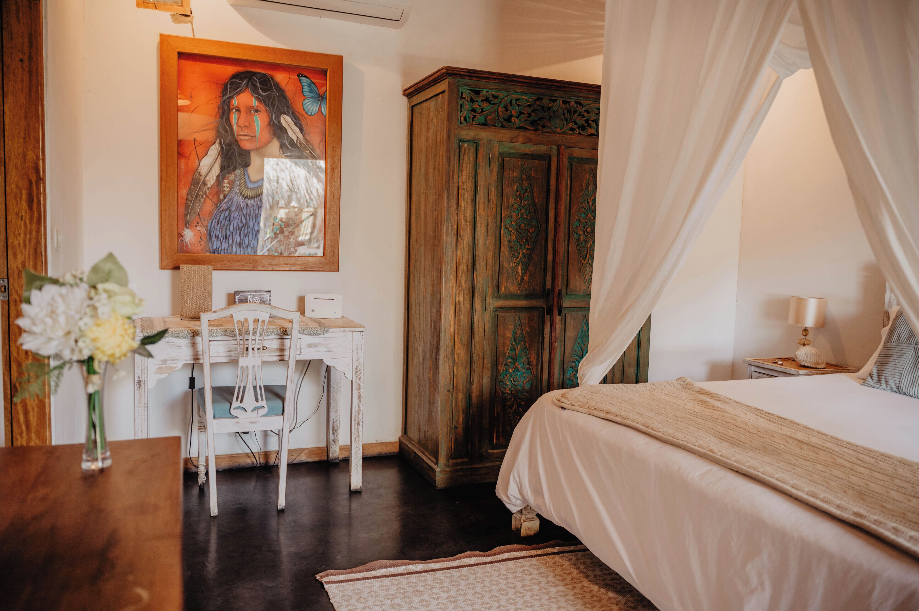 Quarto com cama, escrivaninha, cadeira, guarda-roupa e um quadro na parede.