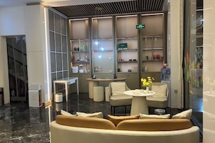 Um saguão de hotel moderno com área de estar, balcão de recepção e exposição de serviços.
