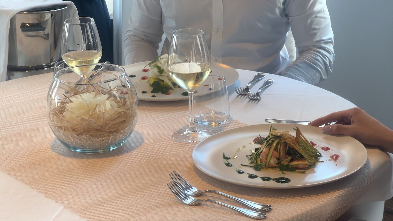 Mesa de jantar com pratos de comida, copos de vinho e talheres.