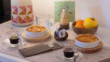 Um ambiente de café da manhã com dois pratos, uma saladeira, uma vela e uma xícara de café.