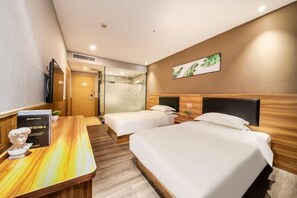Quarto de hotel com uma cama grande, uma cama menor, uma mesa com computador e um quadro na parede.