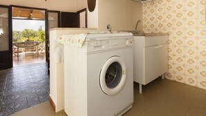 Uma cozinha compacta com máquina de lavar, pia e área de refeições com vista.