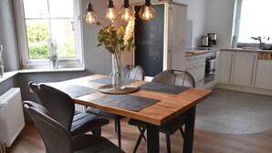 Cozinha moderna com mesa de madeira, cadeiras e um quadro negro.