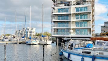 Marina com vários barcos atracados, um edifício em construção com andaimes, e um céu claro.