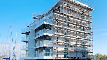 Edifício de vários andares em construção, com vista para o rio, com varandas e design arquitetônico moderno.