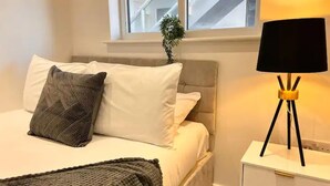 Quarto com cama, abajur e janela com vista para uma escadaria.