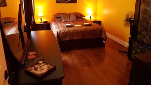 Quarto de hotel com uma cama, abajures, um quadro na parede e piso de madeira.