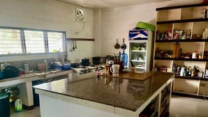 Uma cozinha com bancada de granito, pia, fogão e geladeira.