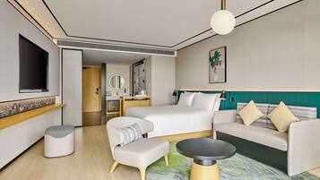 Quarto de hotel moderno com cama, sofá, poltrona e uma mesa pequena. Há uma televisão, um espelho e um quadro na parede.