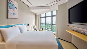 Quarto de hotel com cama grande, televisão de tela plana, vista para a cidade e um quadro na parede.
