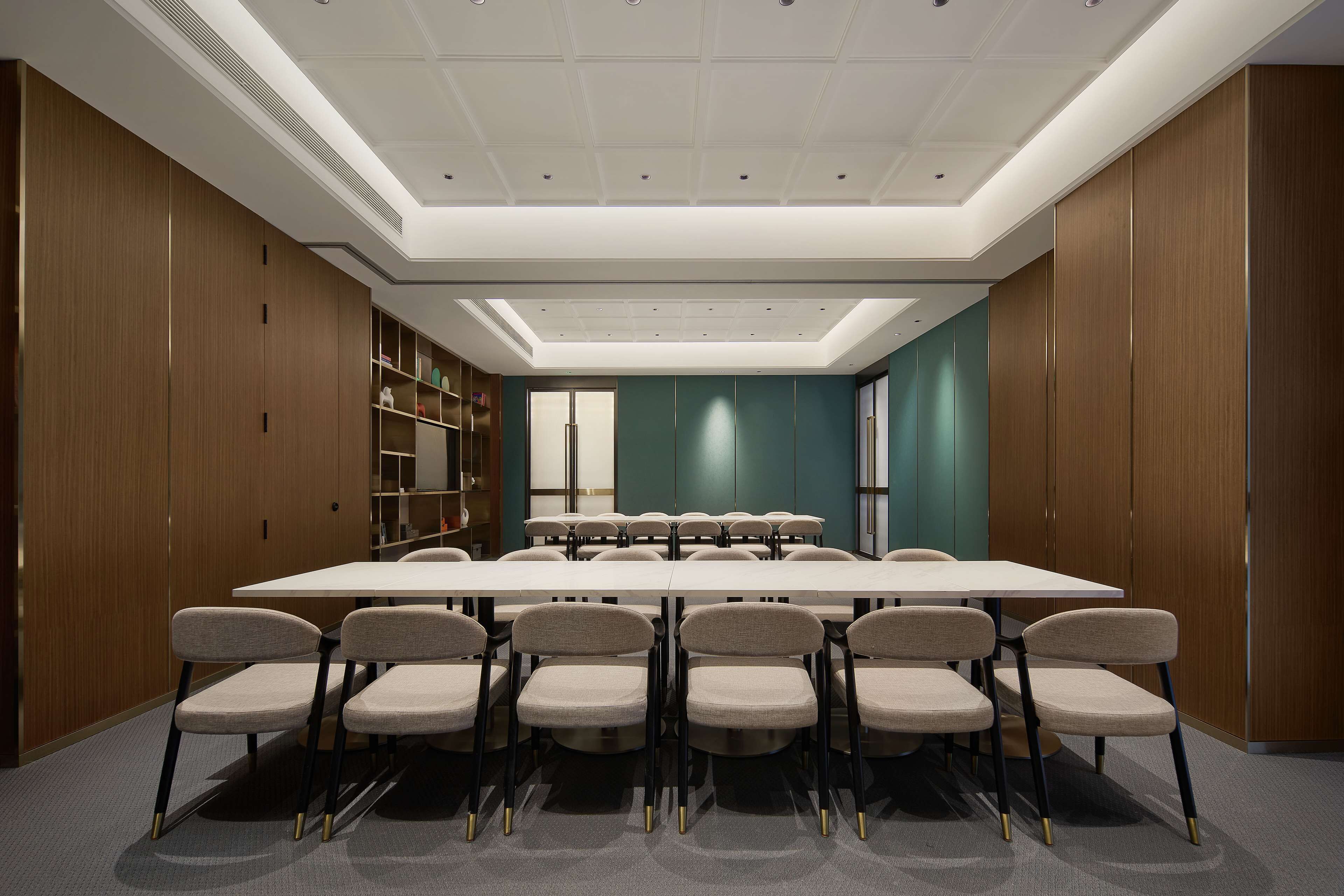 Uma sala de conferência com uma mesa longa e cadeiras, painéis de madeira e um design moderno no teto.