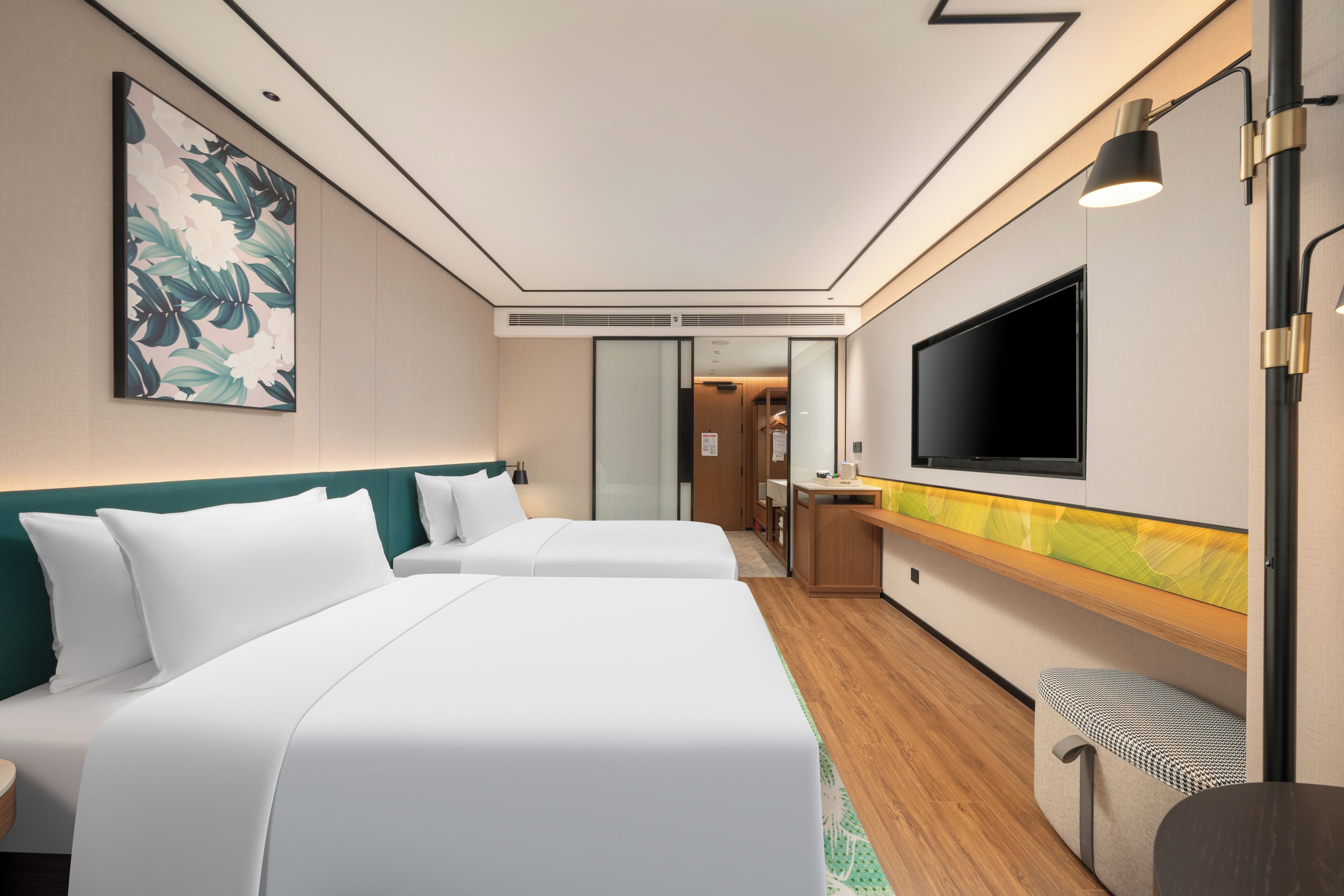 Quarto de hotel com duas camas, televisão de tela plana, escrivaninha e um pequeno espaço de estar.