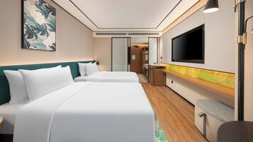 Quarto de hotel com duas camas, televisão de tela plana, escrivaninha e um pequeno espaço de estar.