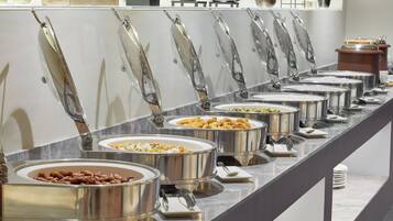 Disposição de buffet com várias estações de comida, cada uma com uma concha e um recipiente.