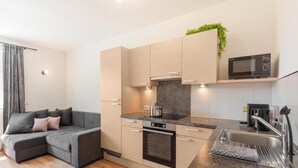 Uma cozinha moderna com eletrodomésticos embutidos, um sofá cinzento e piso de madeira.