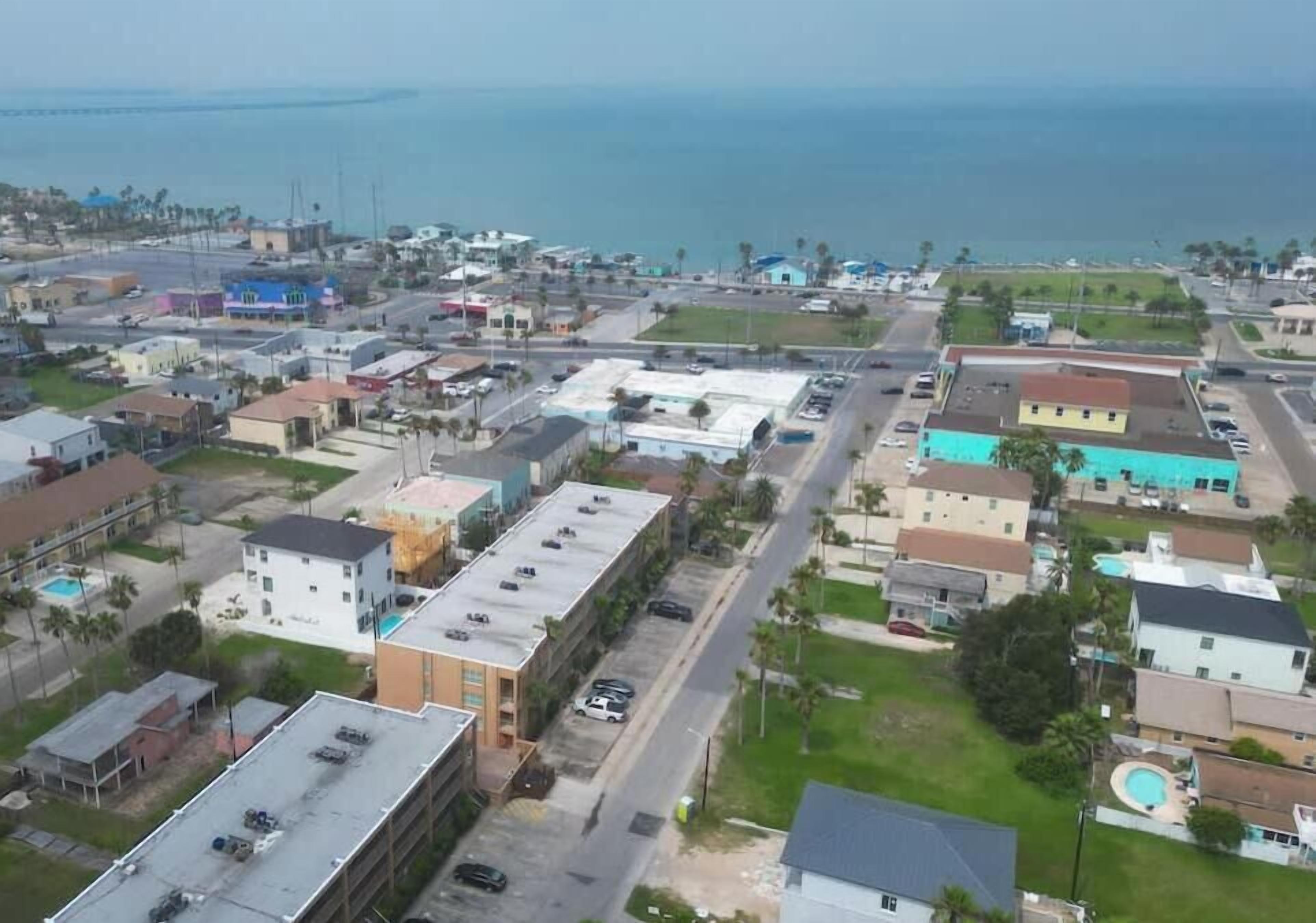 Vista aérea de uma cidade costeira, com edifícios, ruas e uma praia.