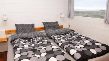 Quarto duplo com duas camas, paredes brancas e vista para o campo.