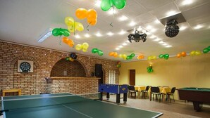 Um quarto com mesa de pingue-pongue, dardos, mesa de futebol de mesa e mesa de bilhar.