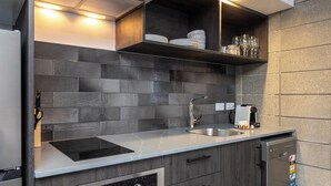 Uma cozinha moderna com armários cinzentos, forno embutido, lava-louças e bancada com pia e cafeteira.