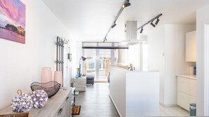 Cozinha moderna com ilha central, piso de madeira e iluminação pendente.