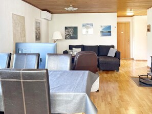 Quarto com teto de madeira, um sofá, uma escrivaninha com abajur e uma cadeira.