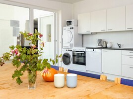 Cozinha moderna com armários brancos, máquina de lavar, forno e micro-ondas.
