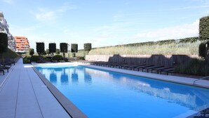Piscina com deck revestido, bancos e cerca de madeira.