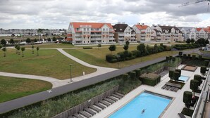 Uma área residencial com piscina, cadeiras de descanso e uma estrada.
