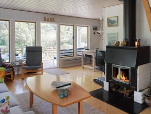 Uma sala de estar acolhedora com lareira, televisão e uma grande janela com vista para o exterior.
