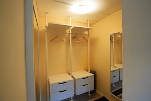 Um closet espaçoso com guarda-roupa espelhado, cabideiro e prateleiras.