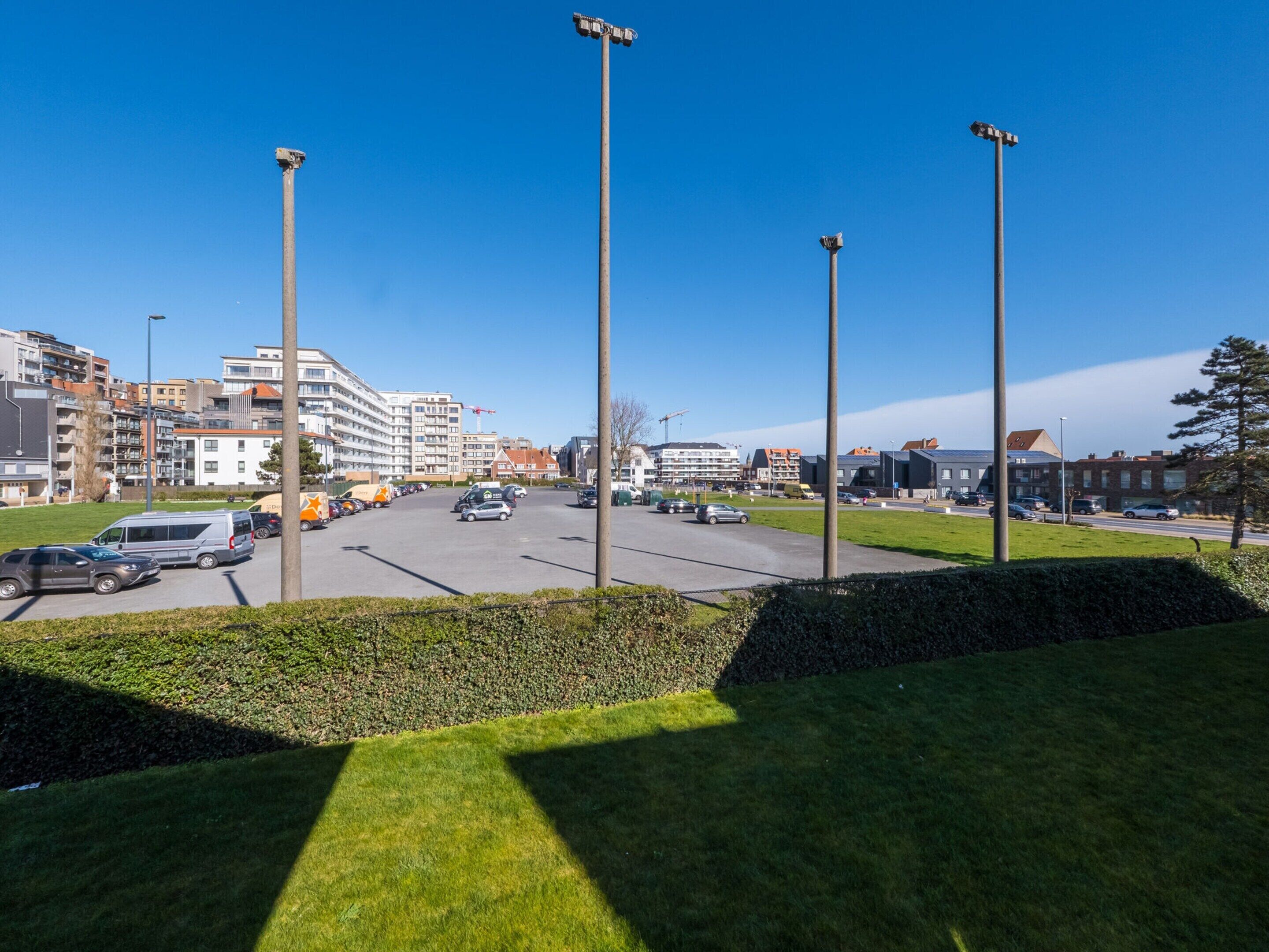 Um estacionamento com vários carros, rodeado por edifícios e vegetação.