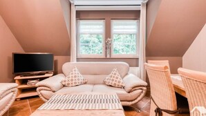 Um quarto aconchegante com um sofá, uma mesinha e uma televisão.
