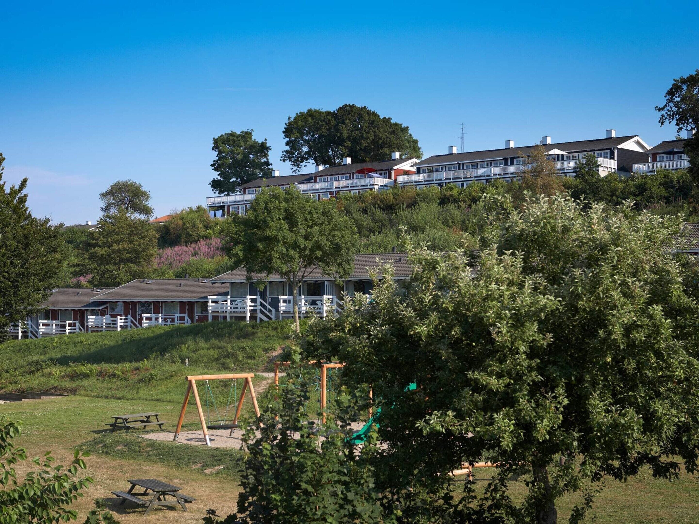 Bairro residencial com casas, um parquinho e mesas para piquenique.
