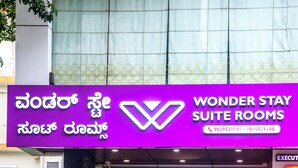 Entrada de hotel com uma placa indicando 'Wonder Stay Suite Rooms' e uma escadaria que leva à entrada.
