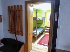 Quarto com beliches, porta de madeira e suporte para esquis.