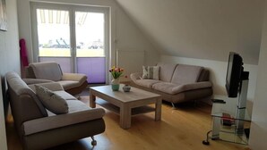Uma sala de estar com dois sofás, uma mesa de centro e uma televisão.
