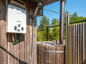 Uma sauna com painel de controle, mangueira e cerca de madeira.