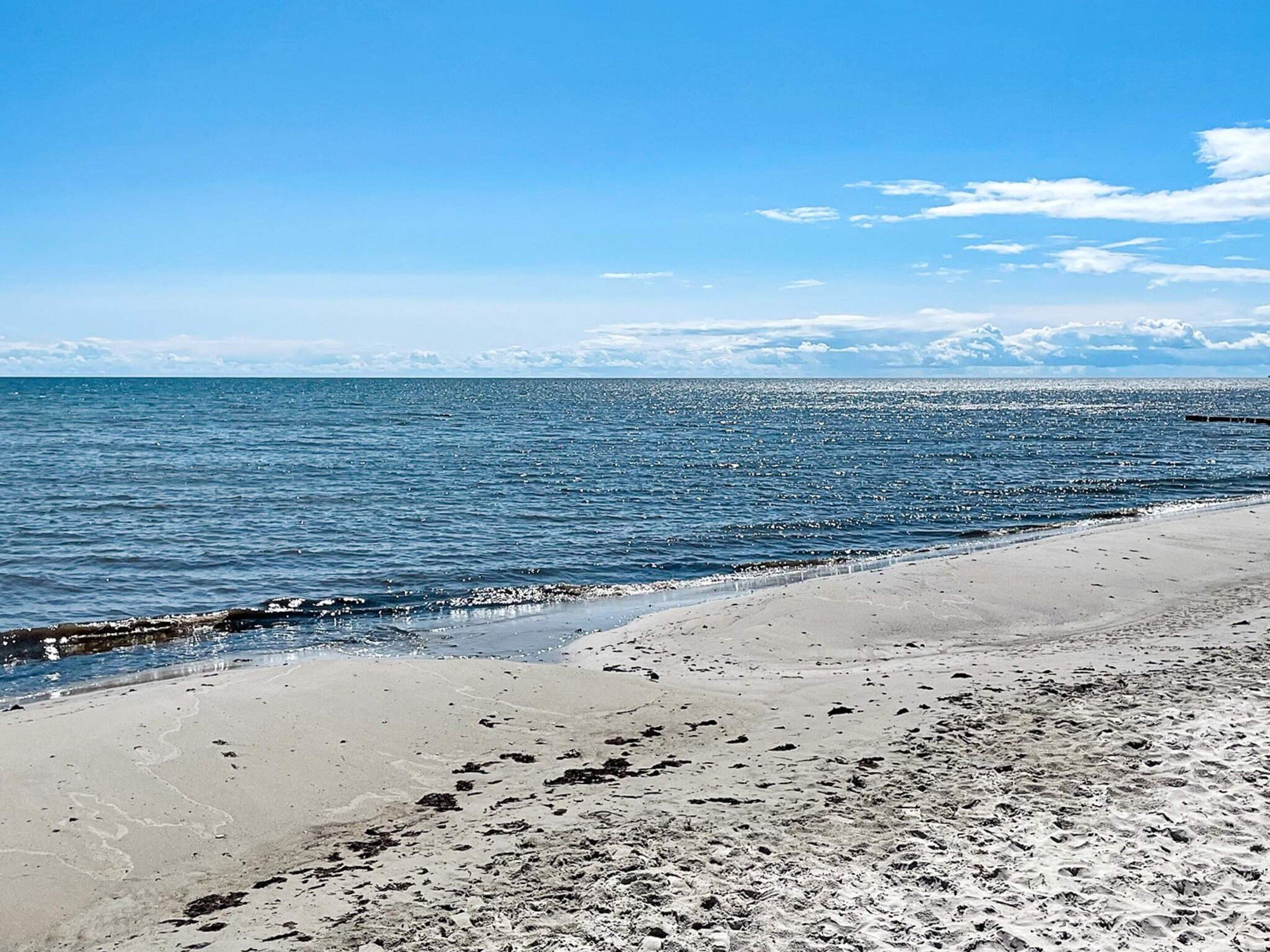 Uma praia com céu claro e mar calmo.