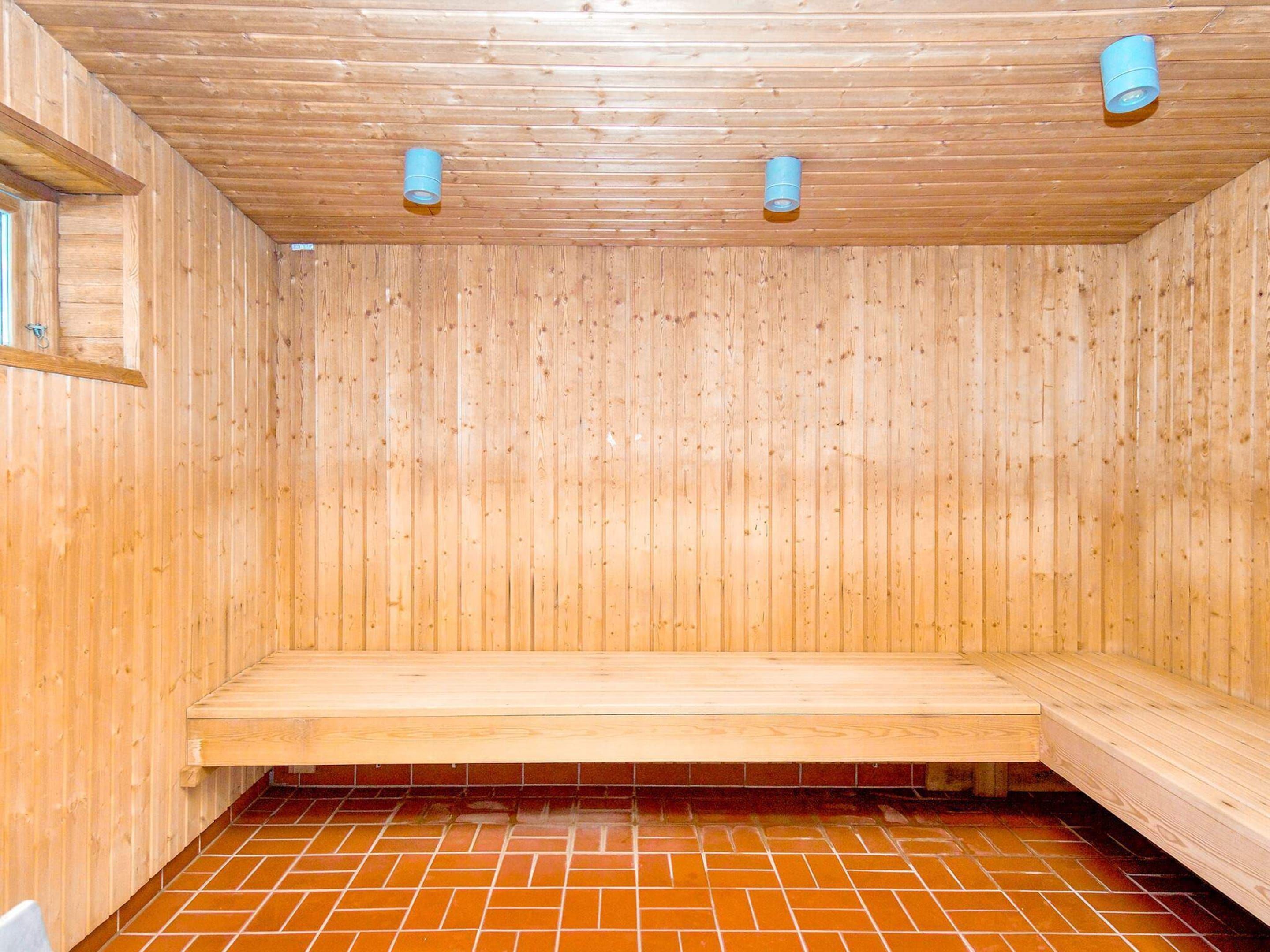 Uma sala de sauna com paredes de madeira, um banco e três luzes no teto.