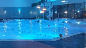 Piscina interior com plataforma de mergulho, marcações de pistas bem definidas e uma escadaria em espiral.