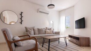 Uma sala de estar moderna com um sofá, uma cadeira de madeira, uma mesa de centro, uma televisão e um aparador.
