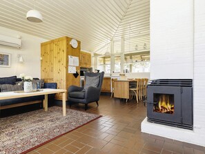 Uma sala de estar aconchegante com sofá, lareira e área de jantar com móveis de madeira.