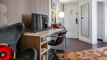 Quarto de hotel com escrivaninha, computador, cadeira e tapete estampado.
