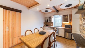 Uma cozinha moderna com armários de madeira, uma mesa de jantar com cadeiras e uma parede com detalhes em pedra.