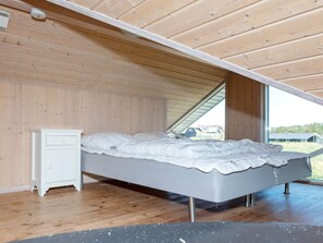Quarto com cama, mesa de cabeceira e janela.