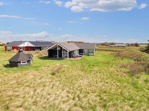 Uma propriedade rural com várias construções, incluindo uma casa principal com varanda ampla e uma estrutura menor.