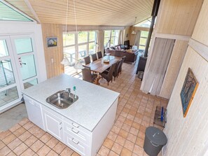 Uma cozinha com pia, armários e uma área de refeições com mesa e cadeiras.