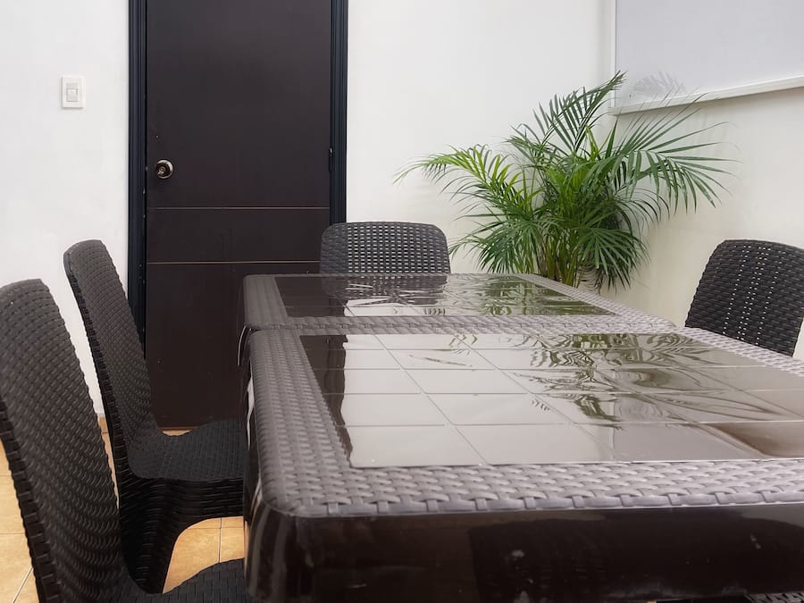 Uma sala de reuniões com mesa de vidro, cadeiras pretas, uma porta com o número 3 e um vaso de planta.