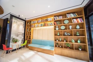 Um quarto com estante de madeira, um sofá azul e uma pequena mesa com cadeiras.
