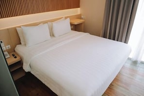 Quarto de hotel com uma cama grande, uma mesa de cabeceira e um criado-mudo.